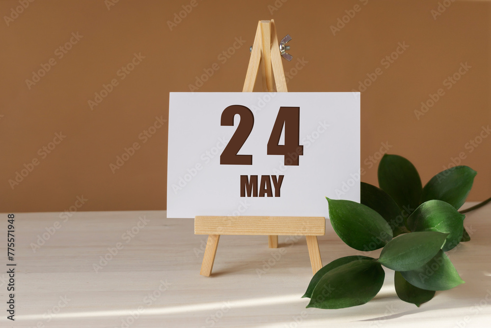 May 24th. Day 24 of month, Calendar date. Green branch, easel with the ...