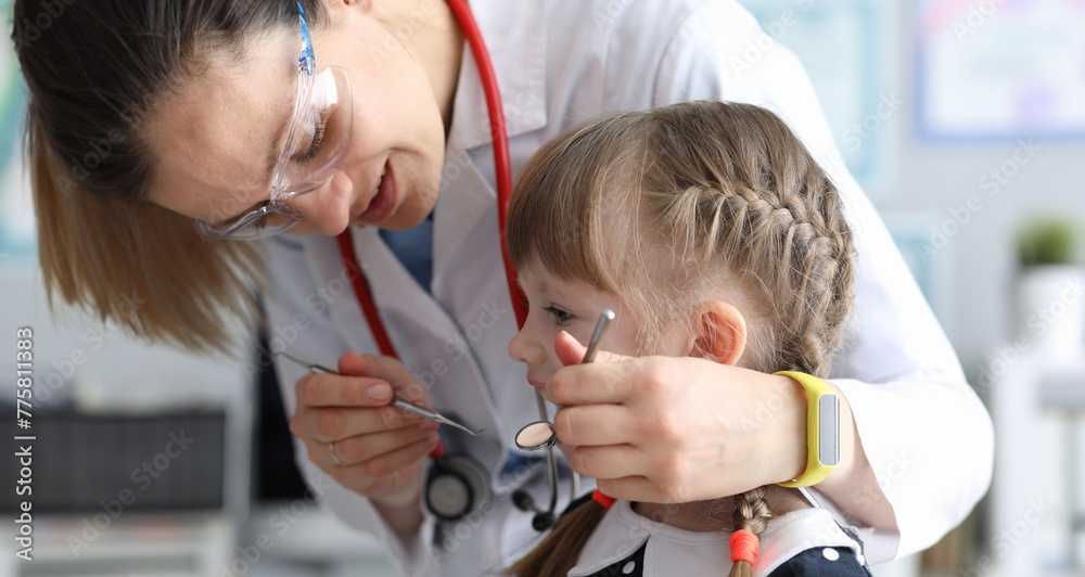 Pediatric dentist examines teeth little girl. Examination oral cavity ...