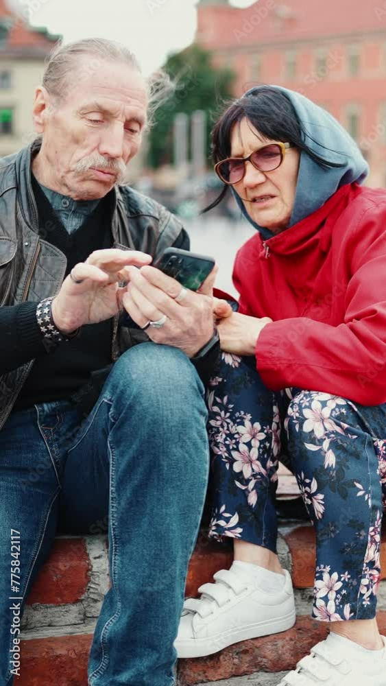 Vertcal video, Elderly married couple sit on the parapet and look at ...