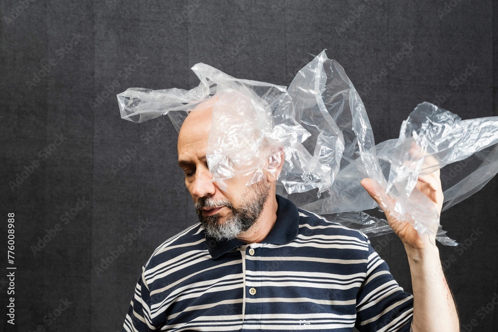 Bald man suffocating with a transparent plastic bag flying over his ...