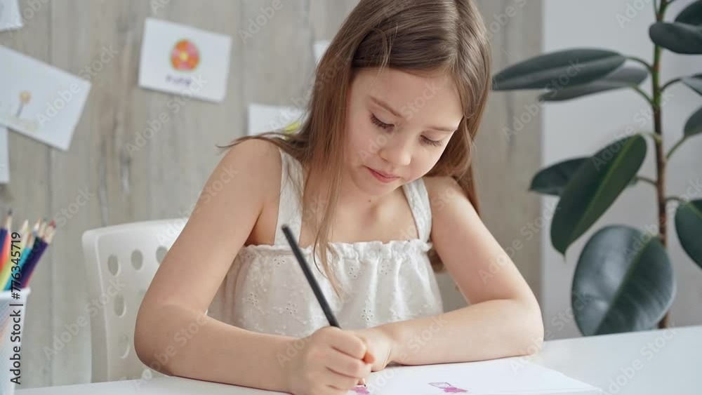 Young girl focused on drawing at the desk at home or school class room ...
