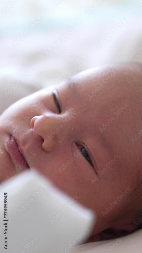 Tiny child is slowly blinking its eyes and gradually falling asleep ...