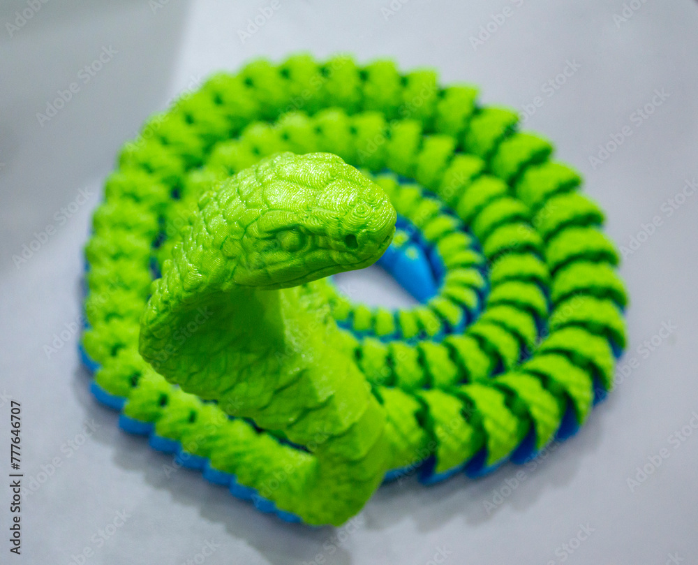 Green snake toy model printed on a 3D printer from melted plastic ...
