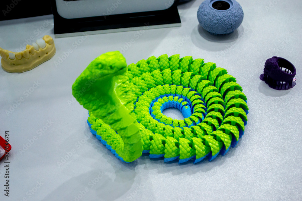 Green snake toy model printed on a 3D printer from melted plastic ...
