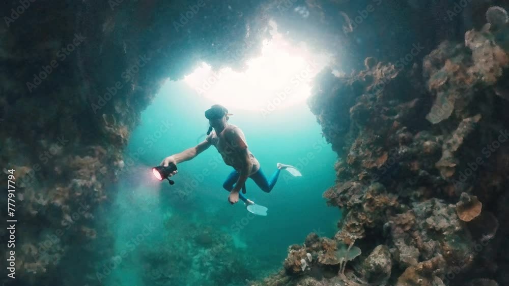 Raja Ampat freediving. Man freediver swims underwater with torch and ...