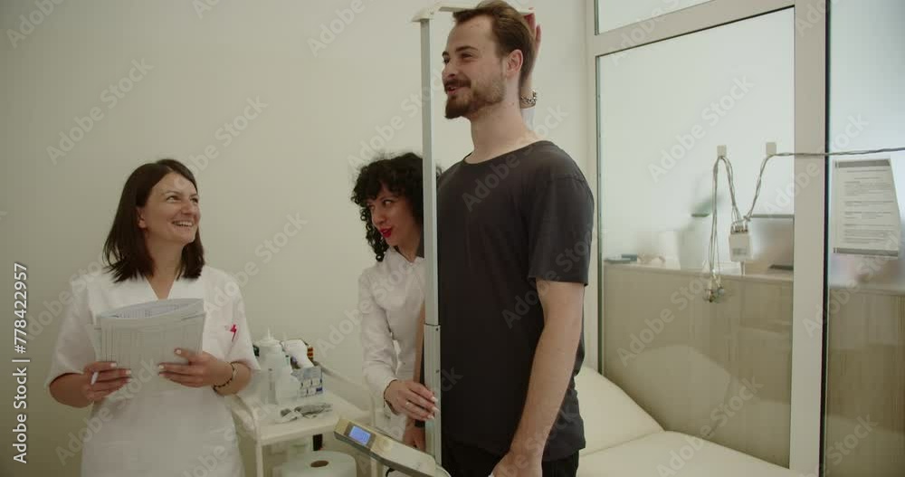 A doctor and a nurse measuring patient's height using stadiometer and ...