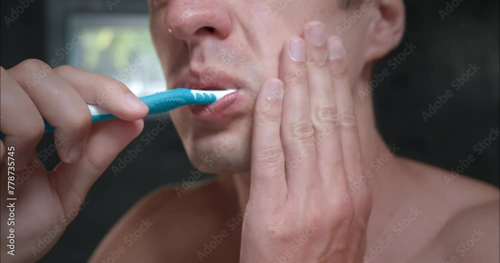Close-up man brushing teeth with toothbrush in front mirror in bathroom ...