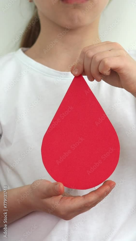 World Children's Blood Donor Day. A girl holds a drop of blood as a ...