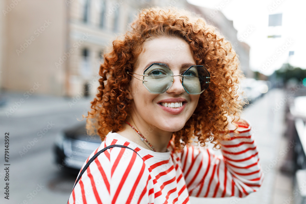 Outdoor portrait of stylish ginger head girl in odd-shaped sunglasses ...
