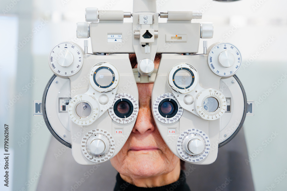 Front view of elderly patient using phoropter in a ophthalmology clinic ...