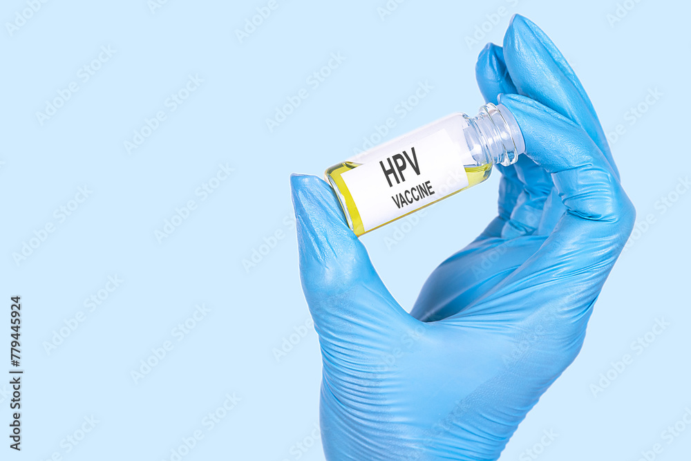 HPV VACCINE text is written on a vial whose ampoule is held by a hand ...