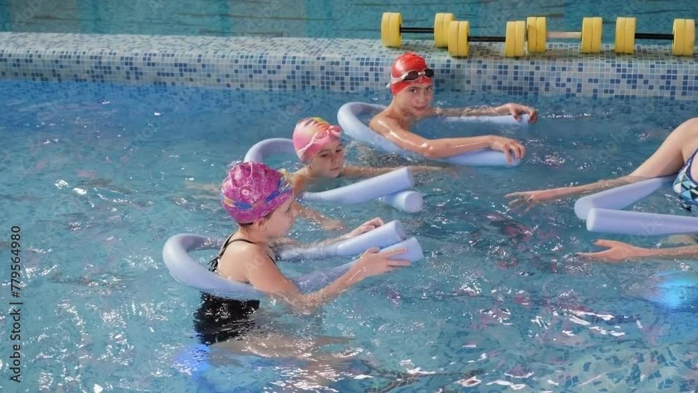 A swimming coach teaches a group of children to swim and dive in an ...