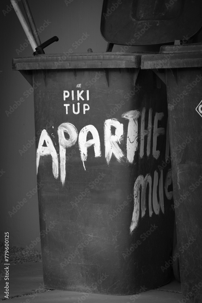 Vertical grayscale of a trash can on the side of a street with words ...