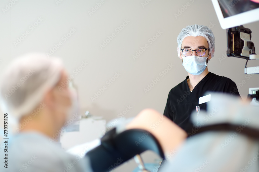 Gynecologist and assistant operating patient in gynecological chair ...
