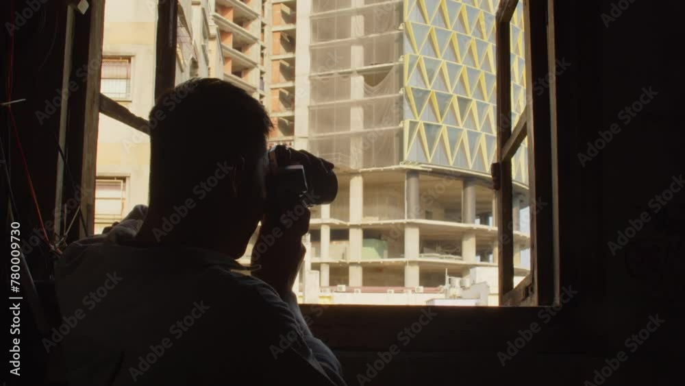 Rear view of silhouette of man taking photo from window of abandoned ...
