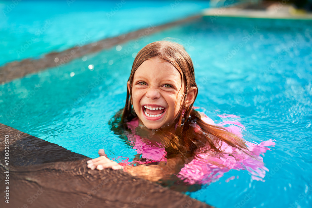 Happy girl in pink swimsuit swims, plays in kid-friendly resort pool ...