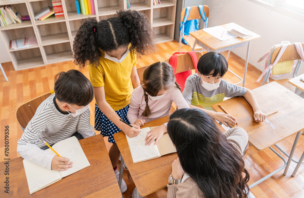 Pupil boy hi five with teacher in classroom at elementary school ...