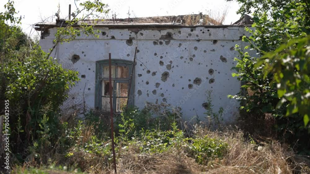 Facade of house with numerous holes from shrapnel, abandoned appearance. Concept of explosion ...