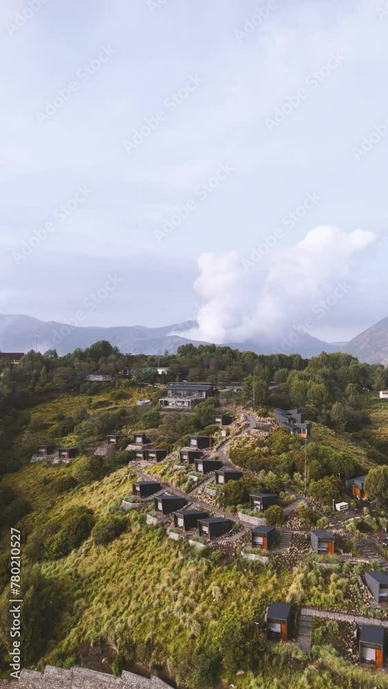 Serene Hillside Village Overlooking an Erupting Volcano in the Distance ...