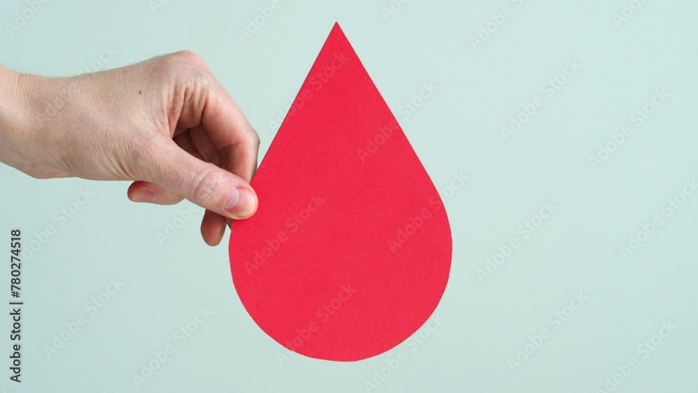in your hand hold a drop of blood cut out of paper on a light ...