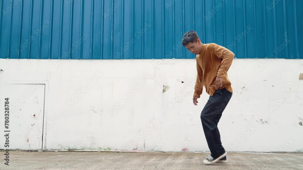 Hispanic man stretch arms and dance street dancing in front of wall ...