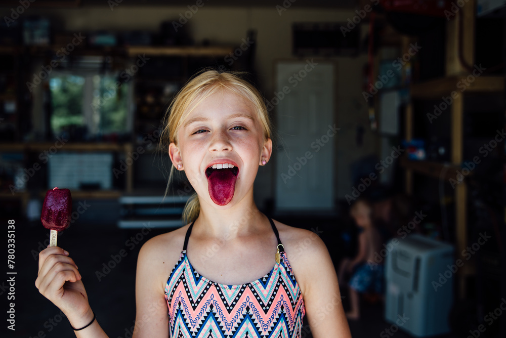 Preteen girl stands in front of garage with popsicle in summer Stock ...