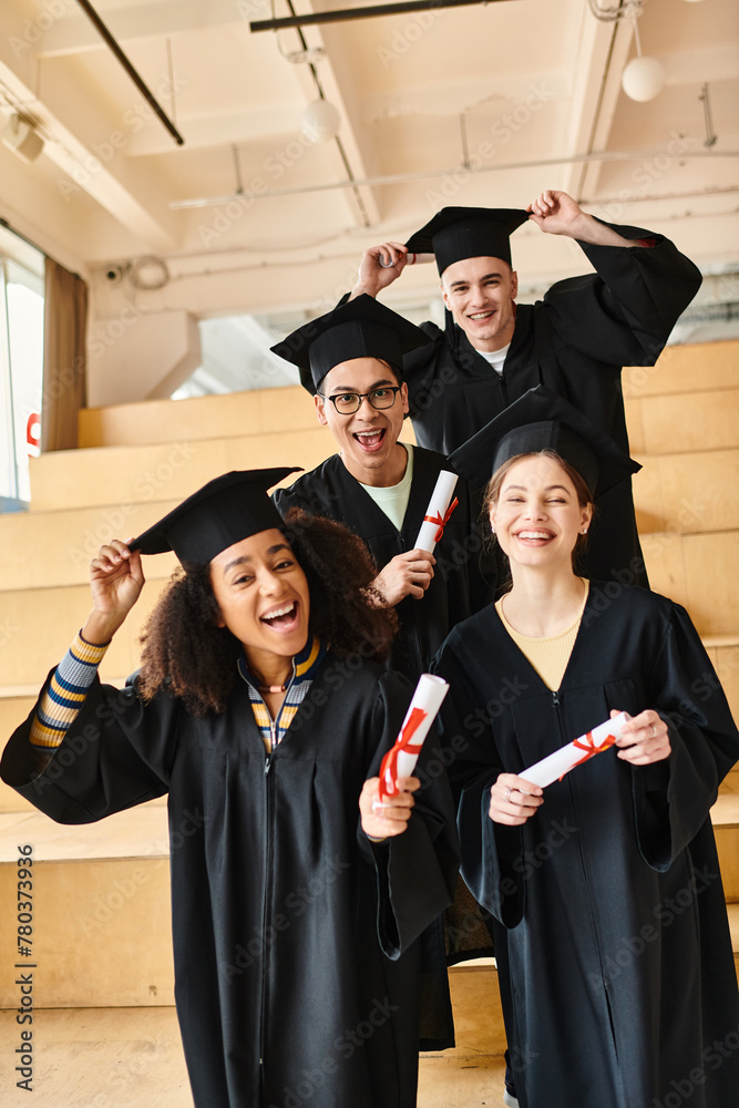 Diverse group of students in graduation gowns and caps smiling for a ...