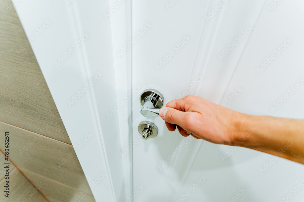 Man opens the door to the room with his hand, white door with silver ...