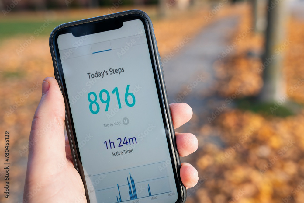 Hand of unrecognizable person showing steps count through smart phone ...