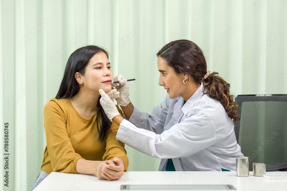 Dermatologist with gloves and pencil marking a patient's face, in ...