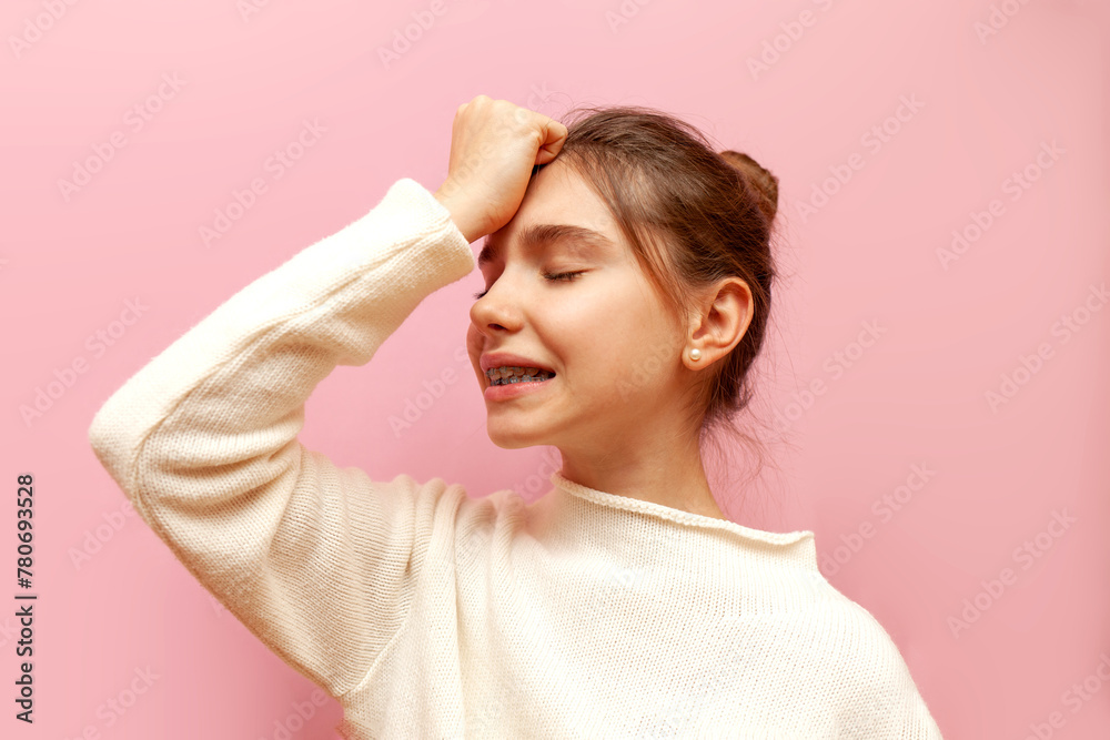 excited teenage girl is worried and shows a facepalm on a pink isolated ...