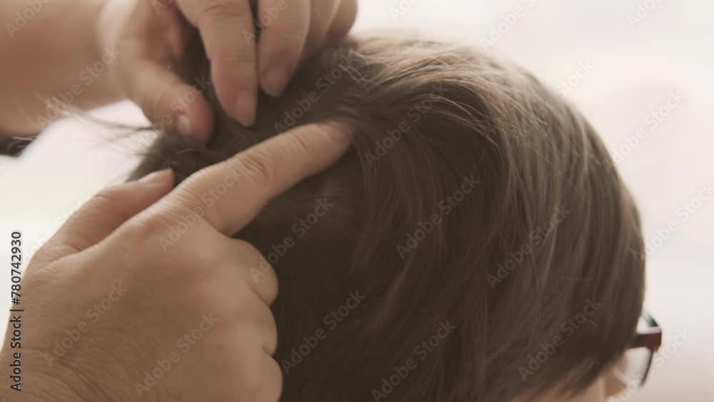 Parent's hands checking school-age child's hair for insects, searching ...