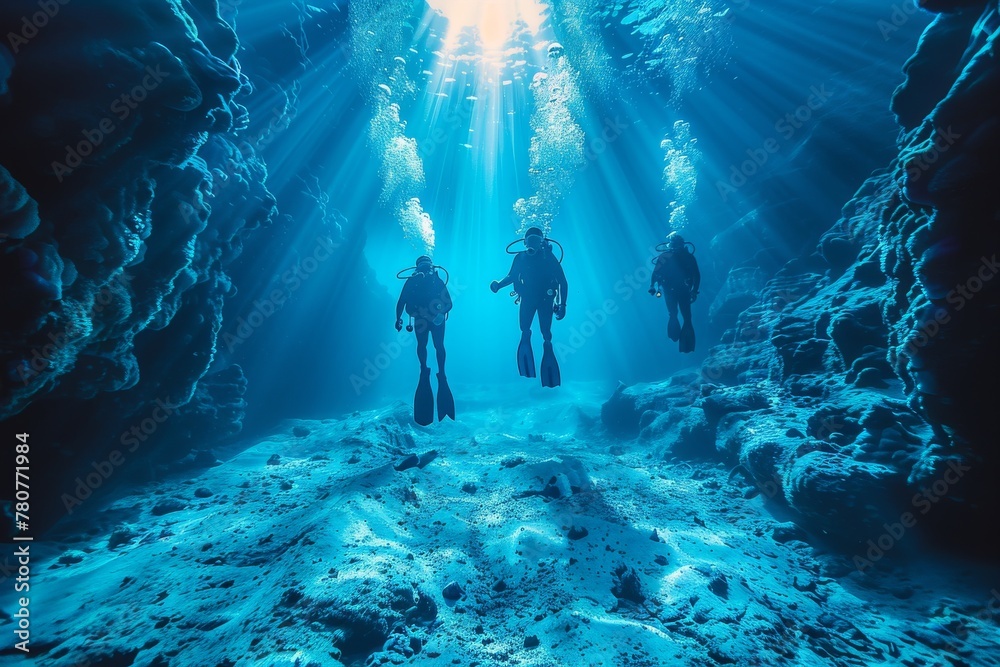 Two scuba divers exploring a deep underwater canyon with sunlight ...