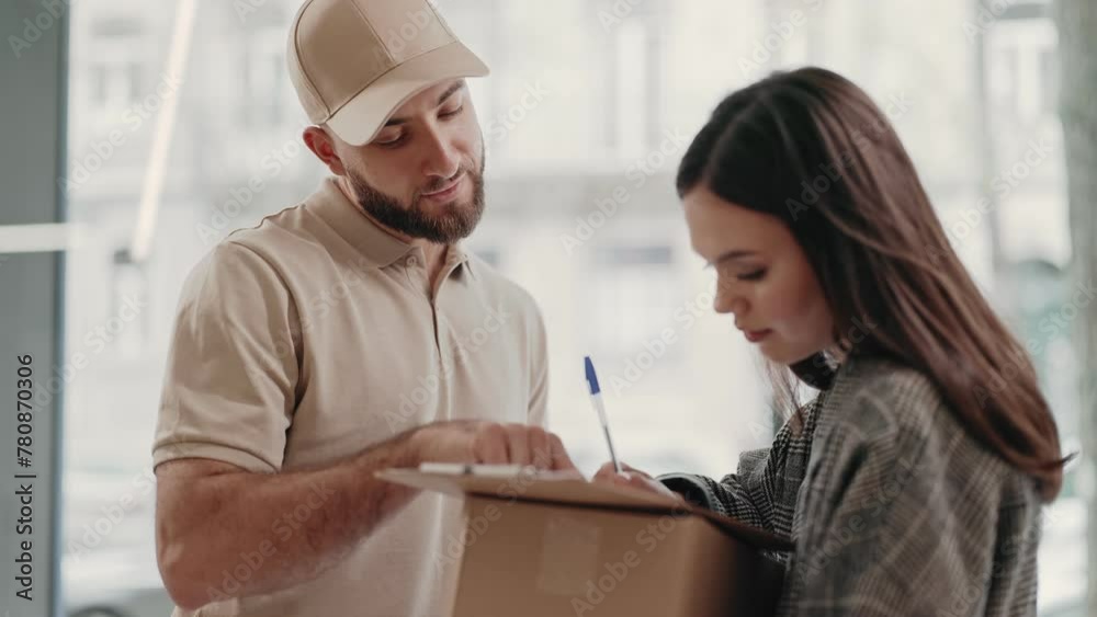 A delivery man waiting while a young woman client signs for a received ...