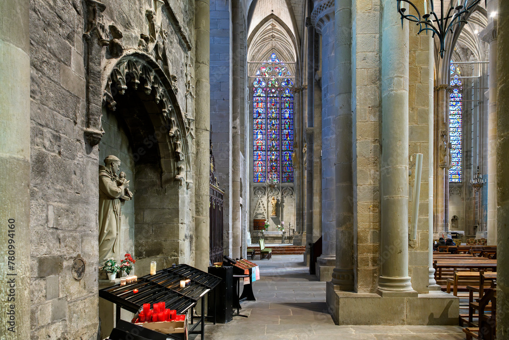 One of the side aisles with a stained glass window in the interior of ...