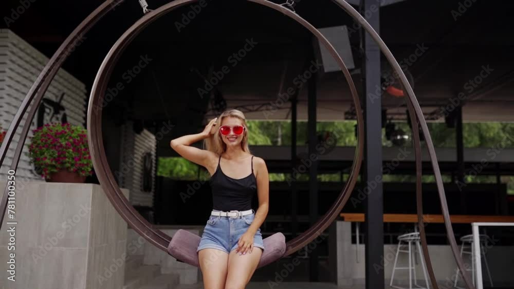 Attractive smiling girl posing, sitting and riding swing at bar counter ...