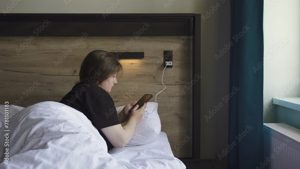 Vidéo Stock Woman with smartphone in bed plugs charger into socket and ...