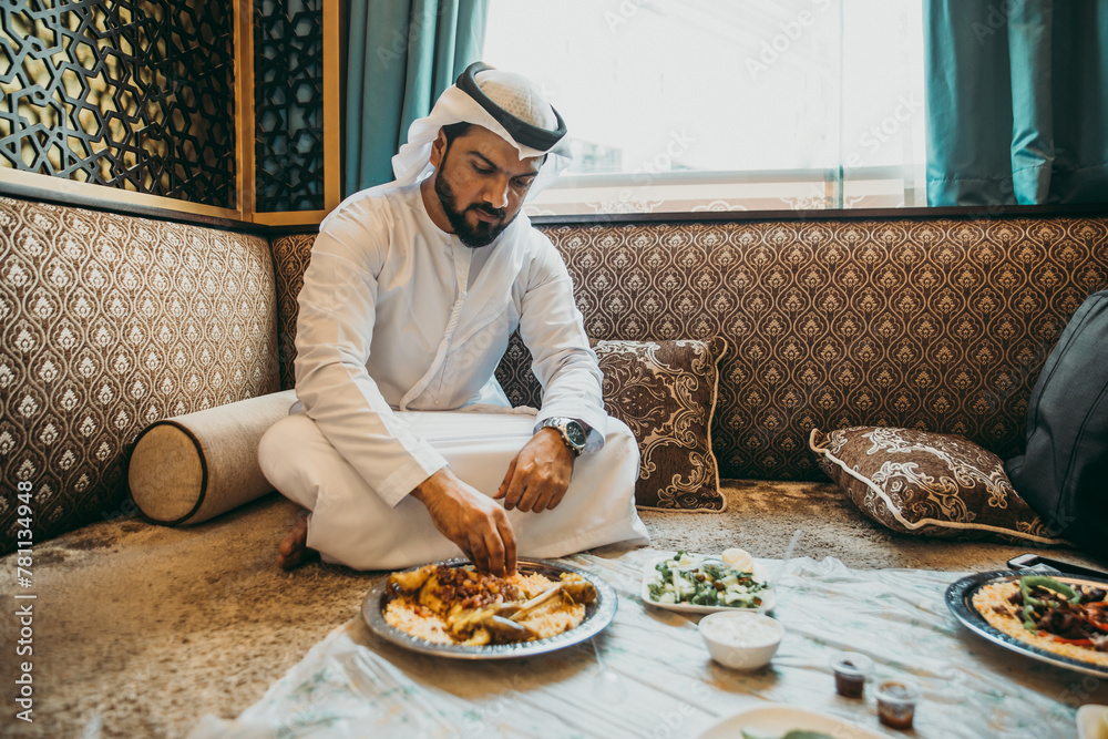 Arabic man with traditional clothes eating chicken mandy, in Dubai ...