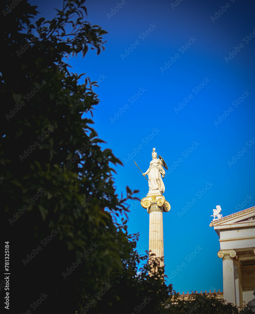 Iconic statue of Athena stands tall beside the Greek flag fluttering ...