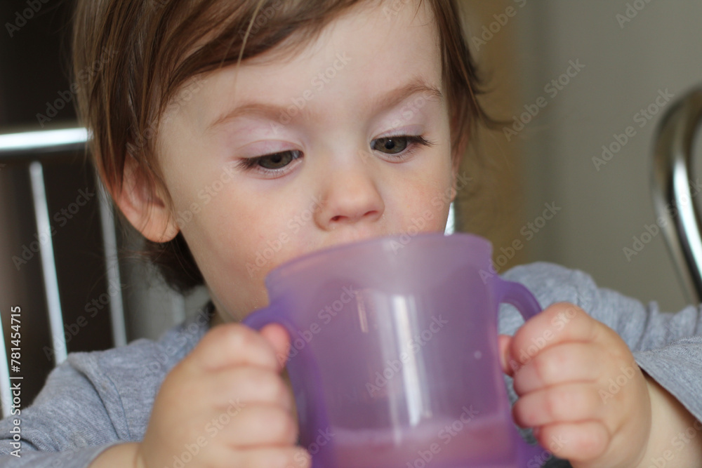 A small child drinks from a two-handed cup. Learning to drink from a ...
