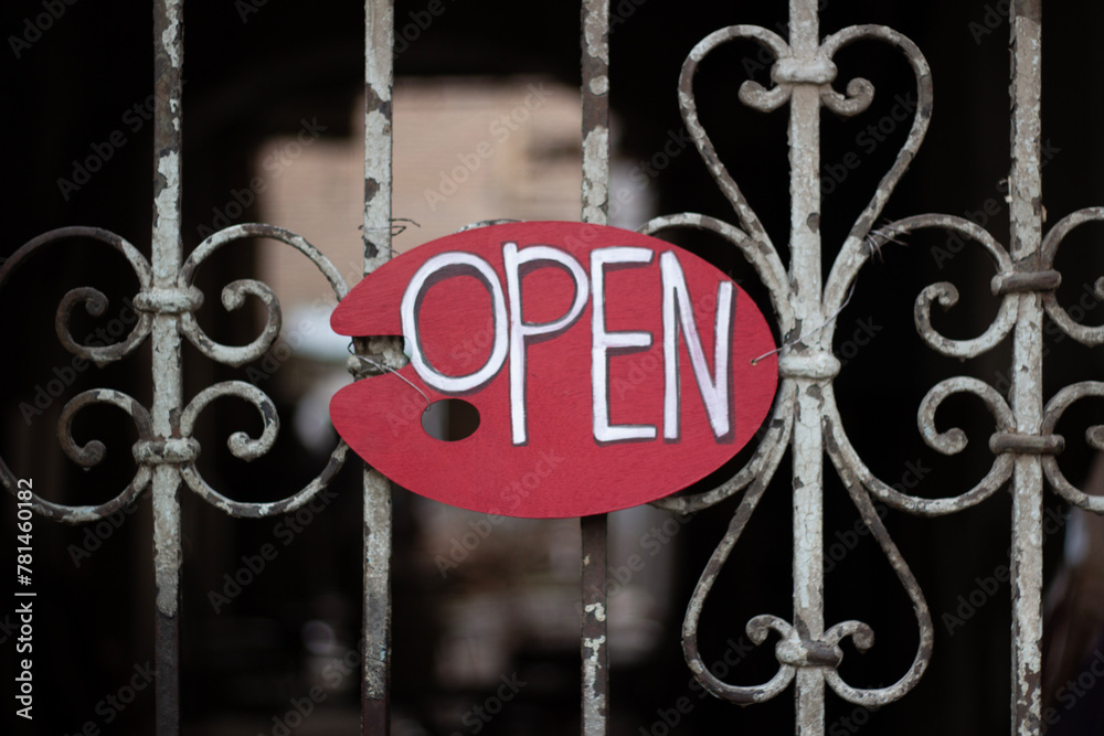 Handwritten Open sign on red oval wooden sign hangs on an old metal ...