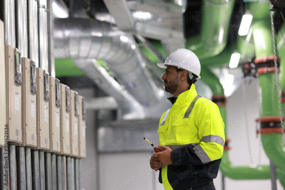 Mechanical engineer with green safety jacket holding laptop and walkie ...