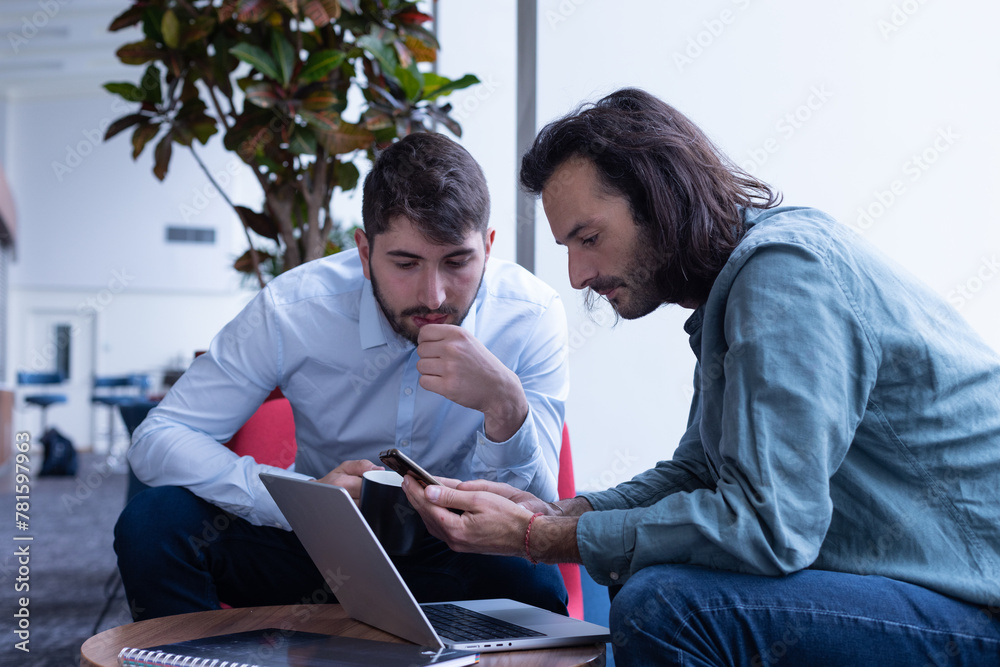 deux collègues discutent autour d'une table basse en buvant un café ...