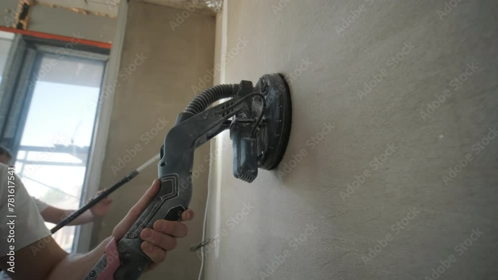 Action shot of construction work, showing a hand guiding a power sander ...