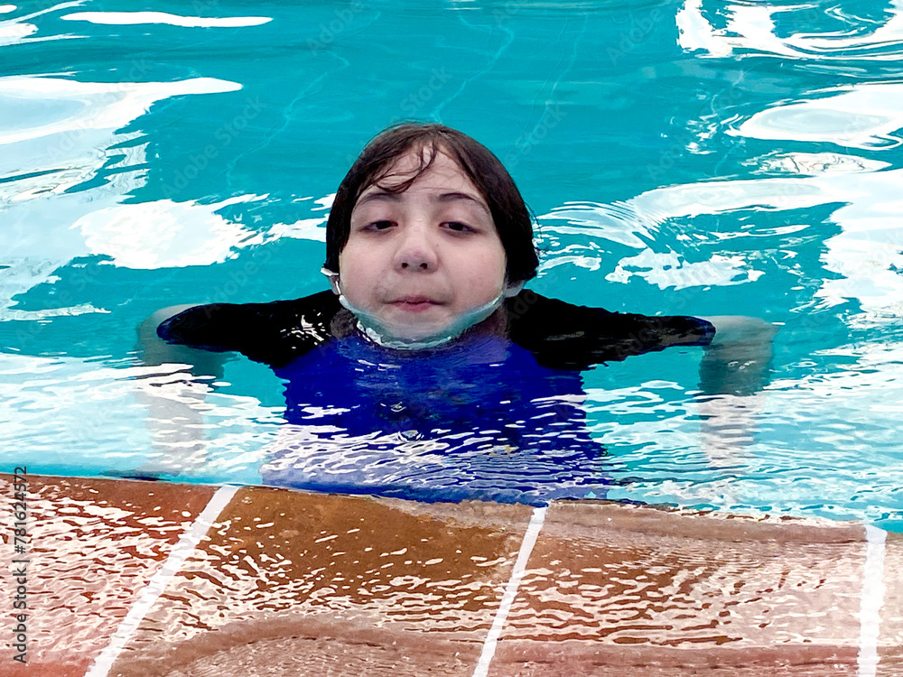 An 11 year old boy swimming in an outdoor swimming pool while on ...