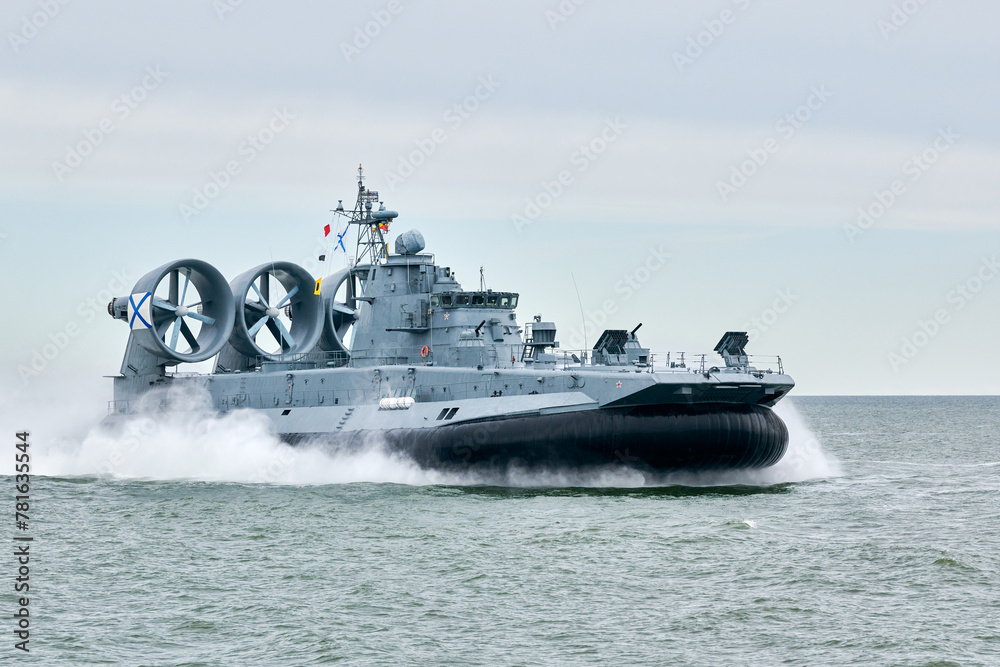 Hovercraft warship armed with armament sails into sea toward military target to attack and ...