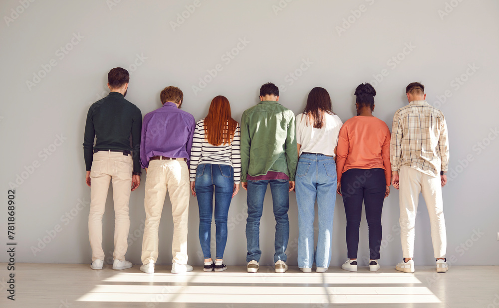 Diverse, silent group of seven people stand in row side by side facing ...
