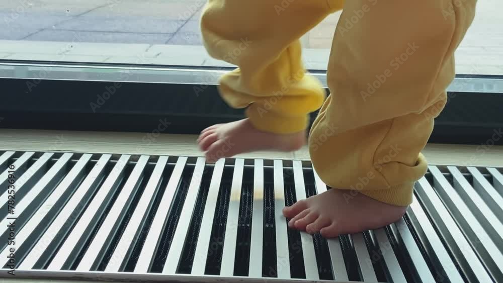 Barefoot child in yellow clothes makes first steps. First steps of ...
