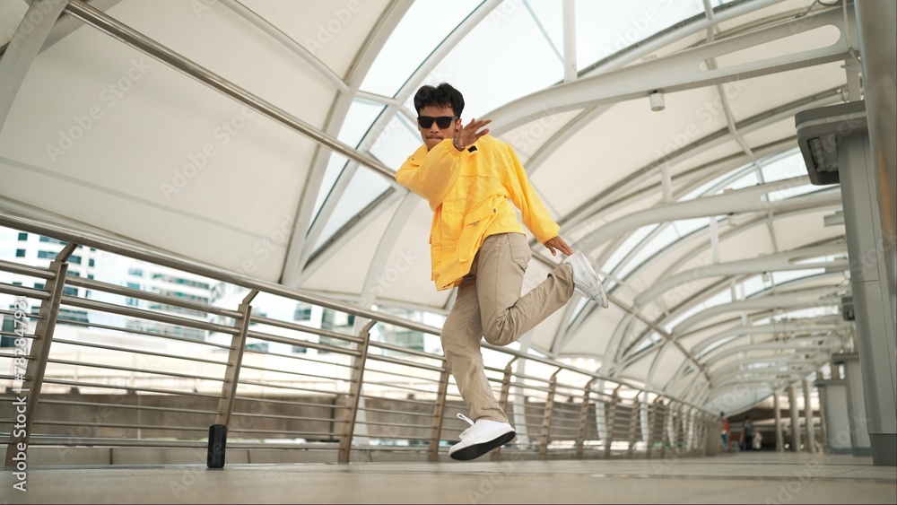 Handsome happy asian hipster dancing while using head spin at corridor ...