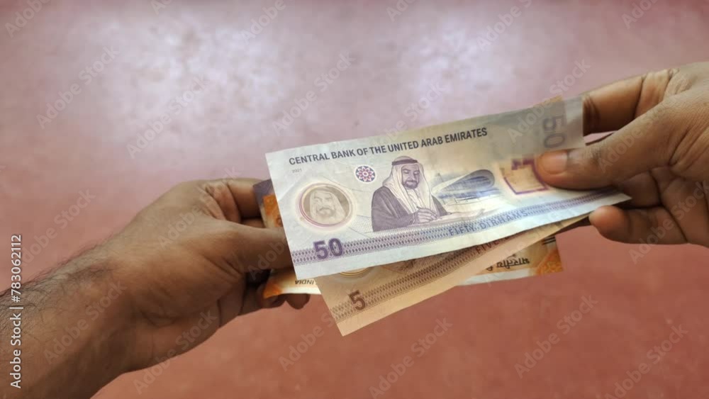 Two hands holding and exchanging united arab emirates dirham currency ...
